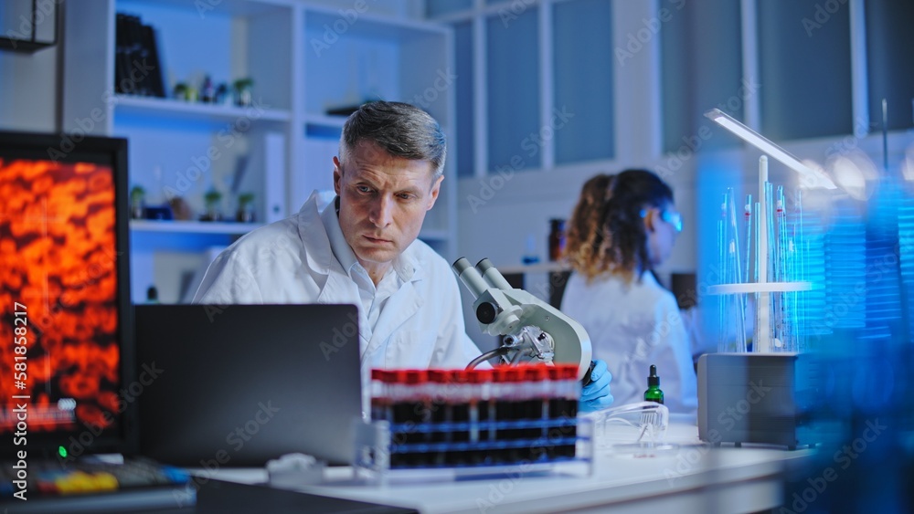 Laboratory workers checking blood samples using microscopes ...