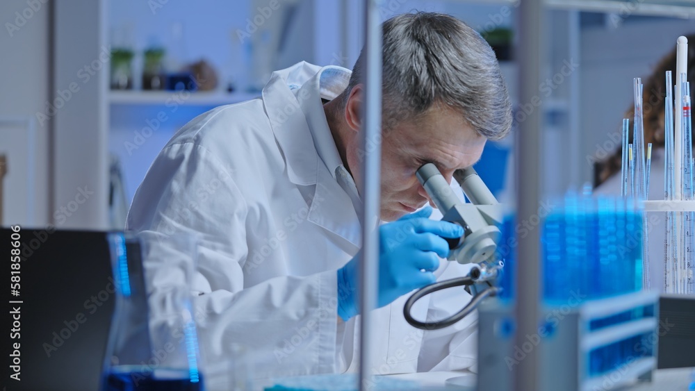 Foto de Medical scientist examining sample cell under microscope in ...