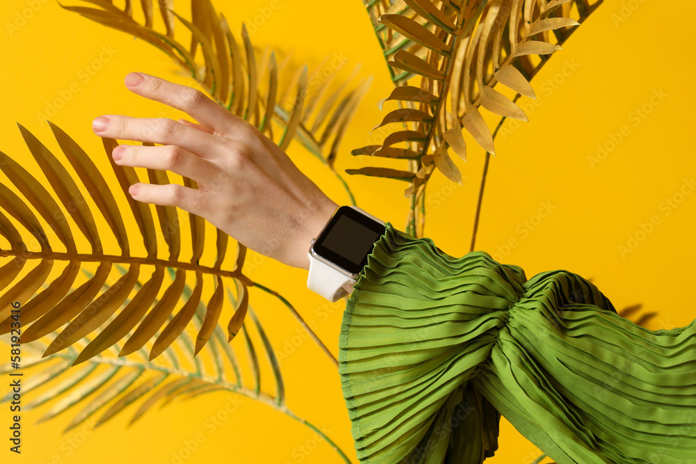 Woman with smartwatch and golden palm leaves on yellow background Stock ...