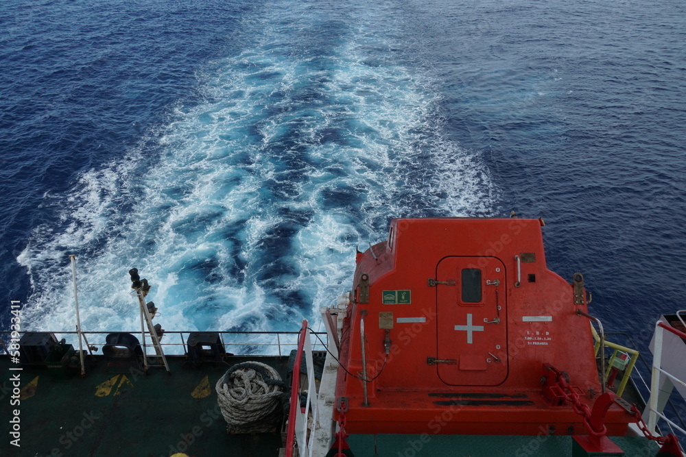 Aft of orange free fall lifeboat with copy space secured on launching ...