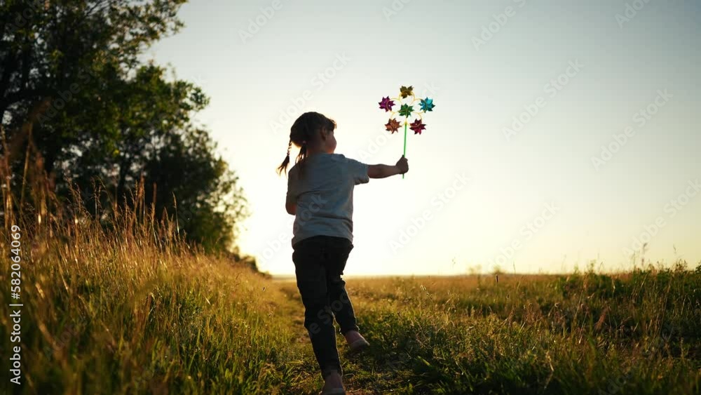 kid girl run after a pinwheel toy in a beautiful city park. kid girl ...