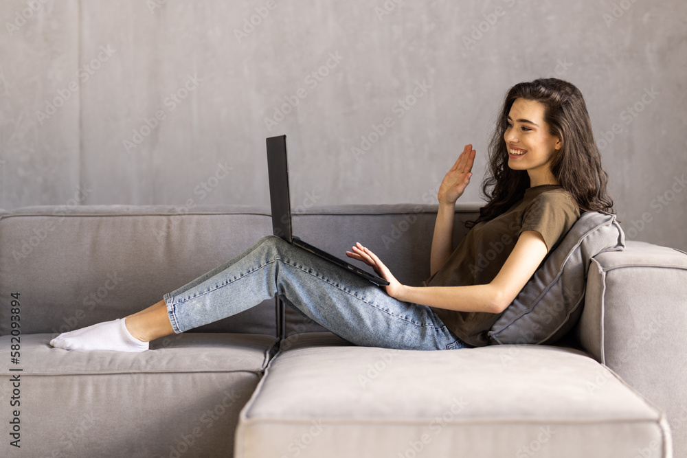 Full length photo of positive cheerful girl sit divan cross legs use ...