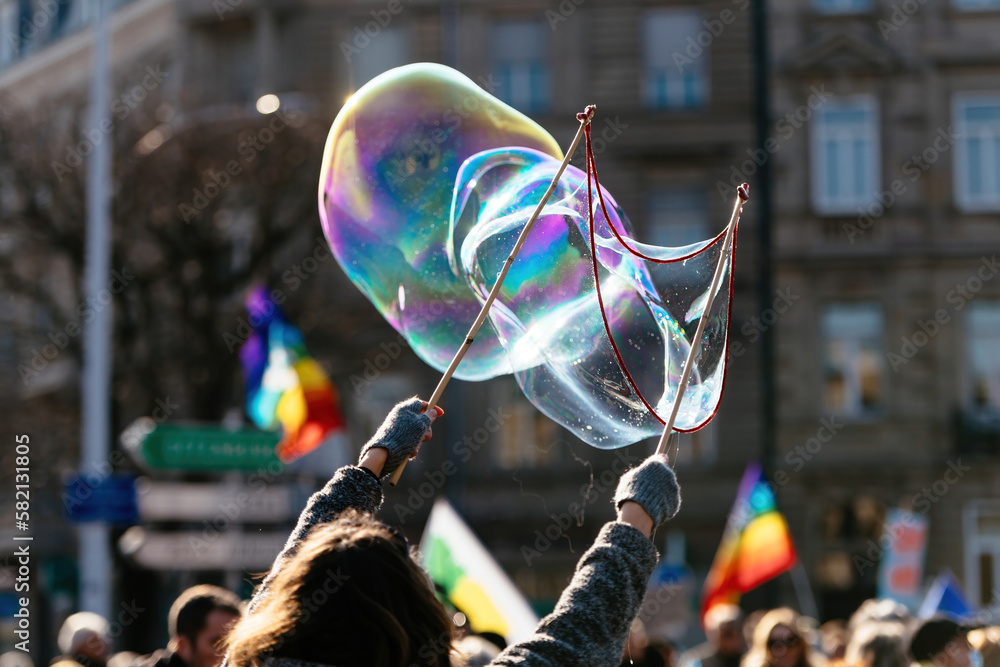 At a vibrant festival, multi-colored bubbles fill the air as someone in ...