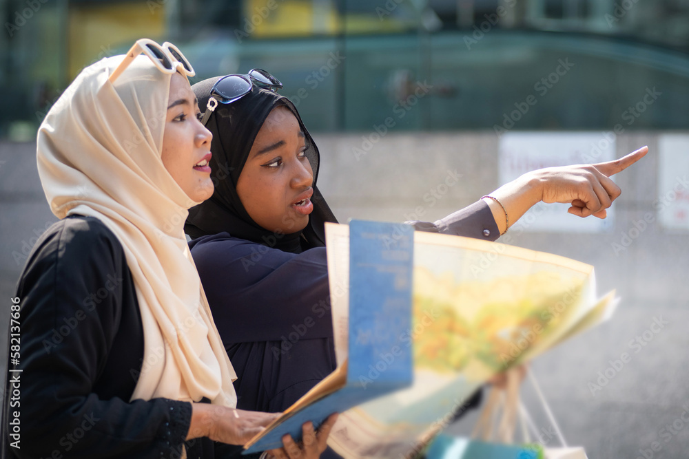 Multiethnic Muslim women wearing hijab enjoy traveling in holiday, hold ...