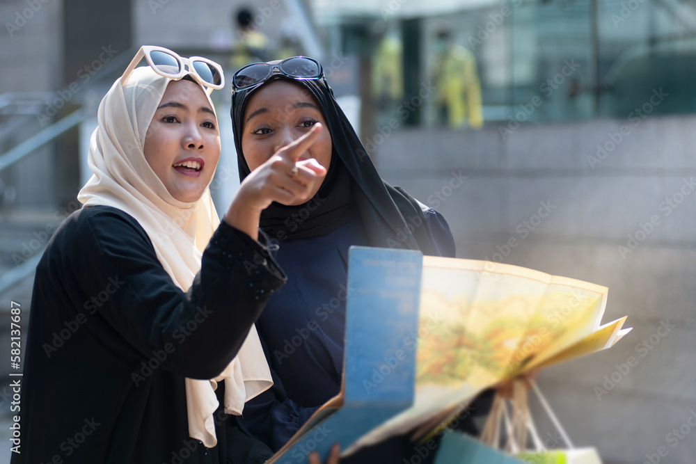 Multiethnic Muslim women wearing hijab enjoy traveling in holiday, hold ...