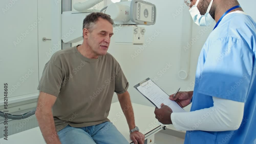 Mature Caucasian man getting X-ray test in modern clinic, African ...
