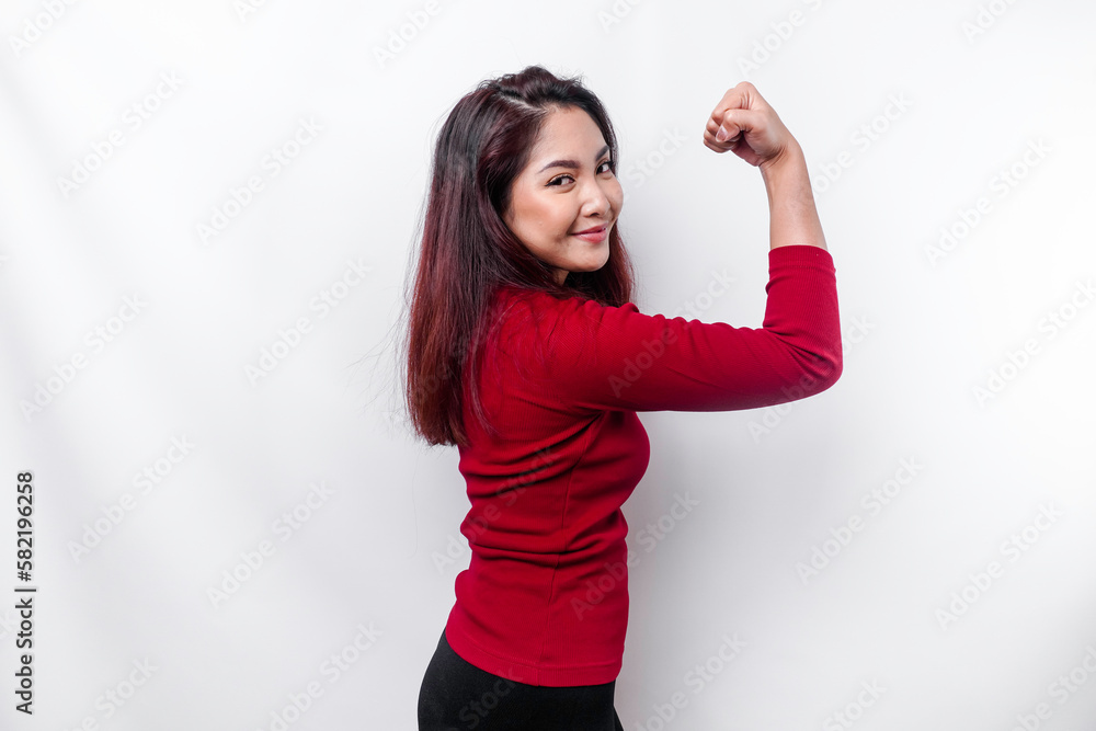 Excited Asian woman wearing a red top showing strong gesture by lifting ...