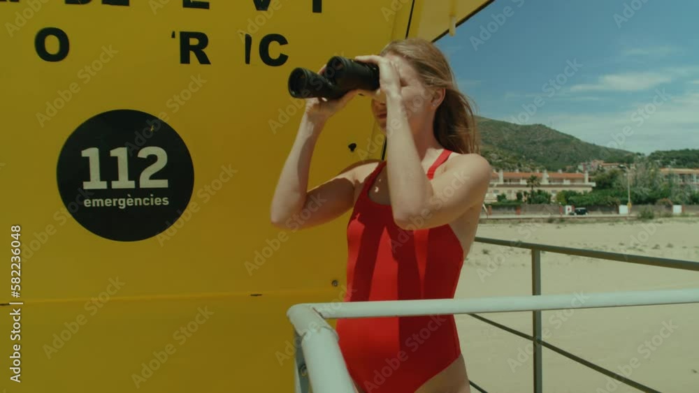 Female lifeguard keeps watchful eye on the bay. She scans the sea with ...
