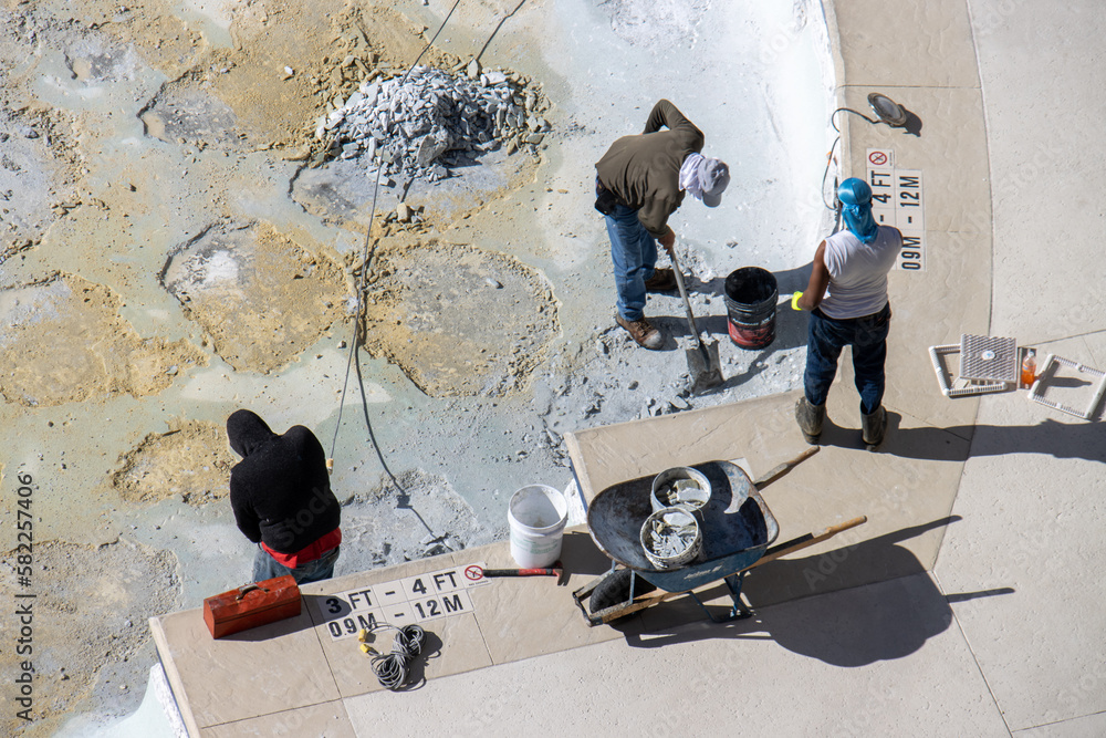 construction workers shoveling broken up cement, rubble into buckets ...