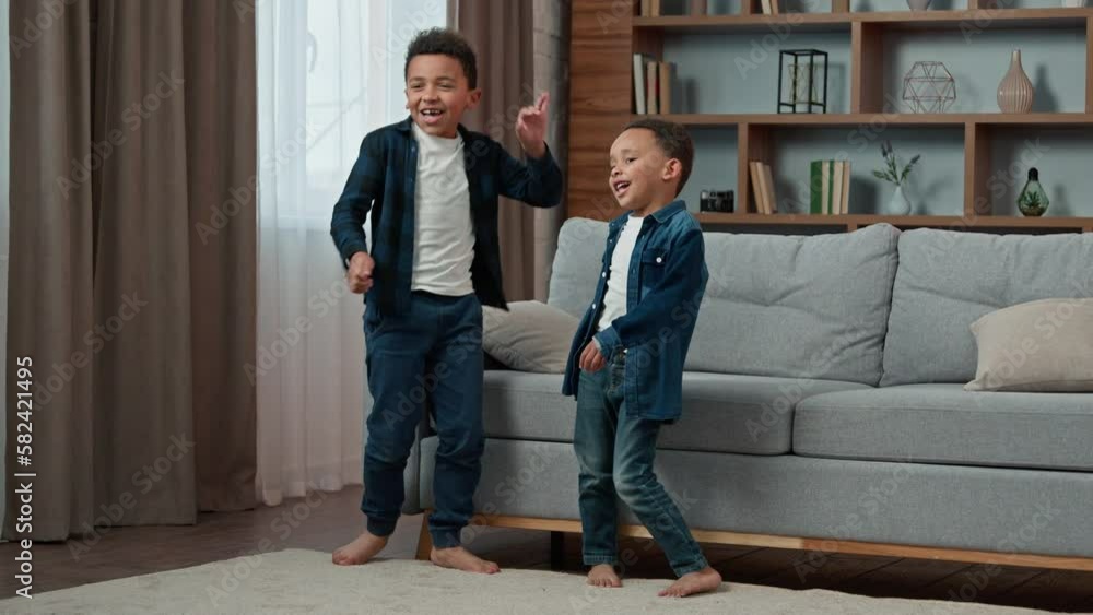 Two ethnic boys little children dancing to music in home living room ...