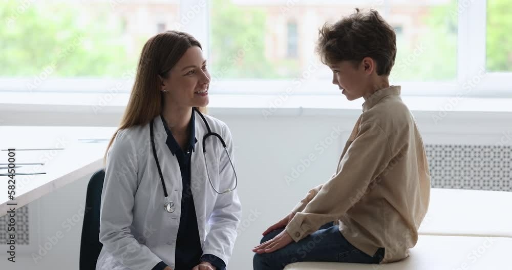 Engaged caring pretty female pediatrician with stethoscope talking to ...