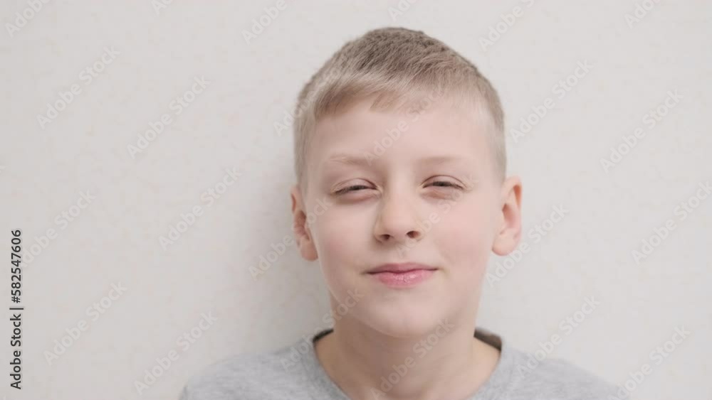 child with a sly narrowed gaze looking at camera. Upset male child ...