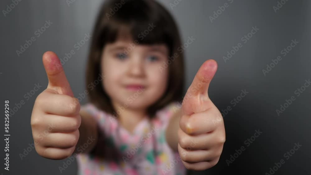 Vidéo Stock A little girl of preschool age shows a thumbs up gesture on ...