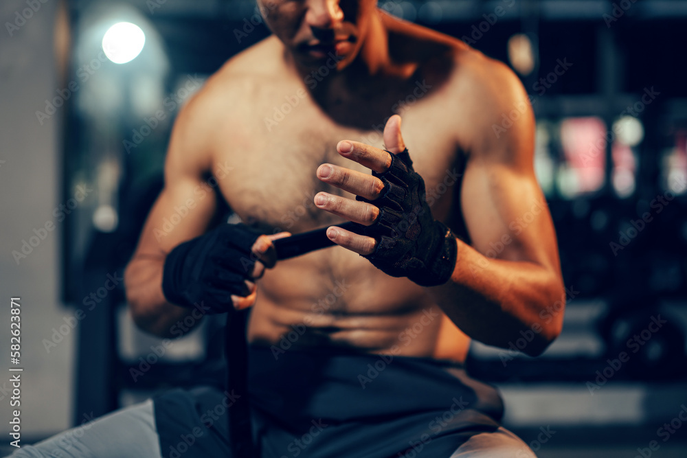 Athlete bodybuilder wearing sport gloves on hand for preparing exercise ...