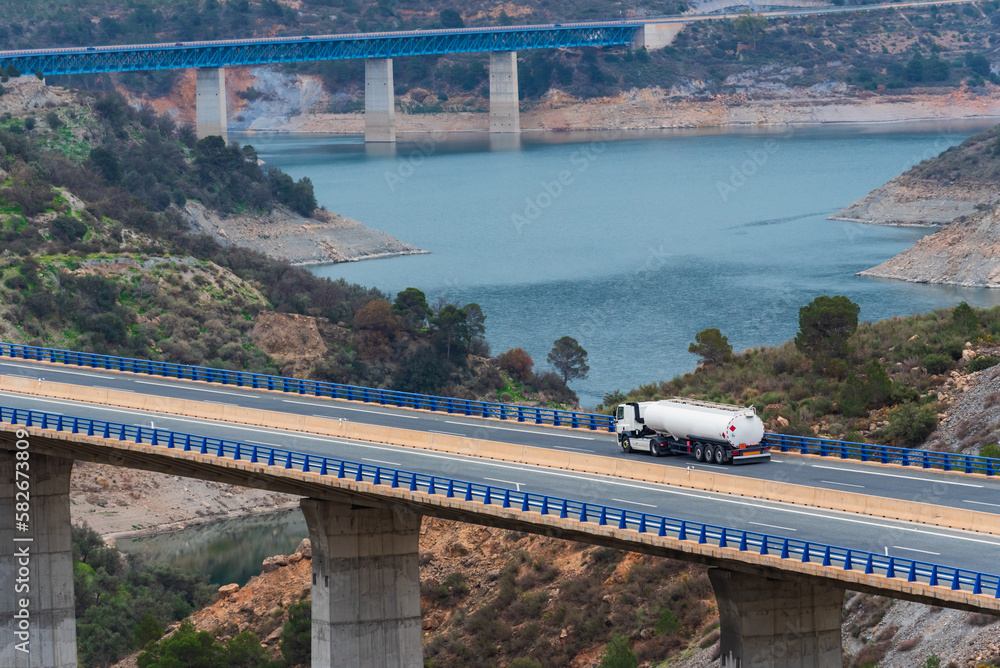 Tank truck with dangerous goods plates driving through a viaduct over a ...