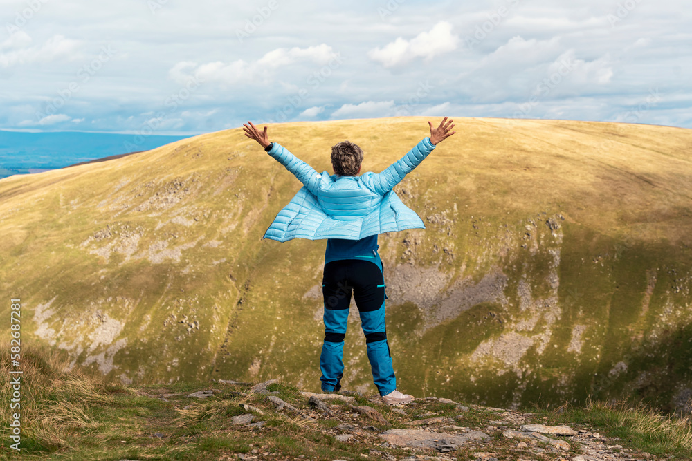 Woman reaching the destination and on the top of mountain opening arm ...