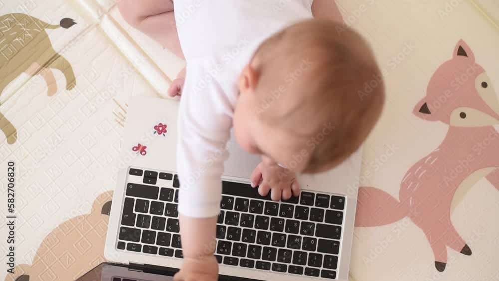 Baby hands is typing on laptop. Hebrew and English keyboard. Top view ...