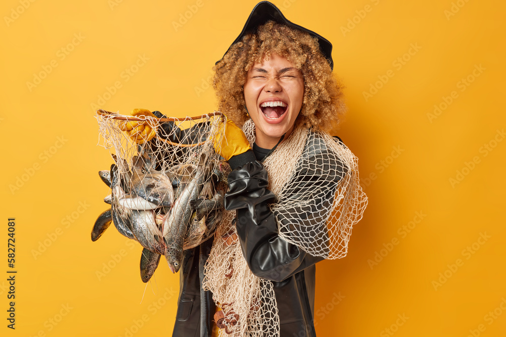 Emotional fisherwoman holds caught fish in net feels very happy to have ...