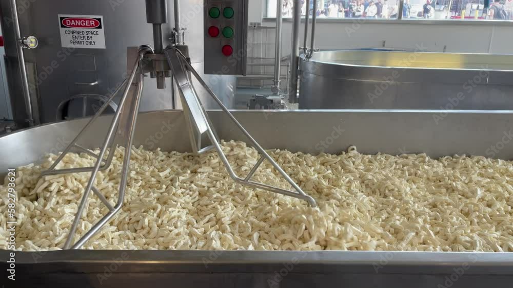 Cheese factory. Big special mixer stirring cheese in the large vat ...