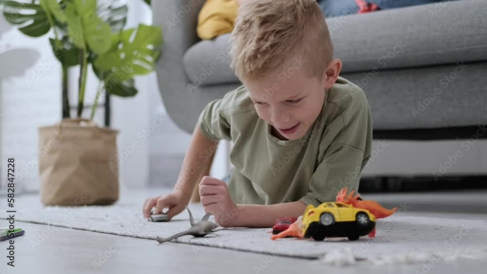 Vidéo Stock little boy playing on floor dinosaur and cars toys while ...