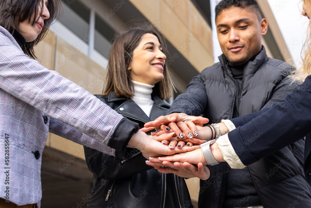 Group of successful young people interlocking hands in the street ...