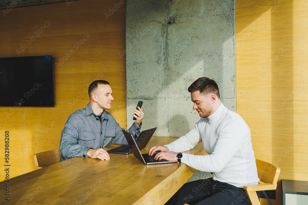 Two confident young people are sitting together at a table and one of ...