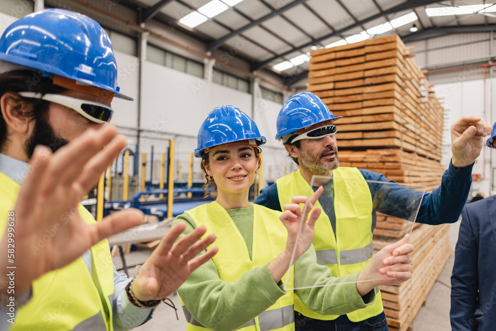 Engineers wearing smart glasses touching transparent screen in factory ...