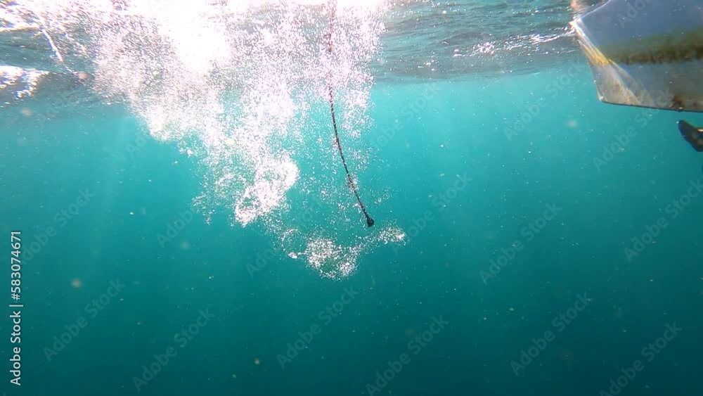 Fishing rod is pulled into water breaking calm surface and whipping up ...