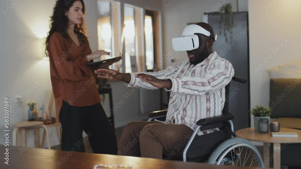 Medium full shot of black man in wheelchair wearing white VR headset ...