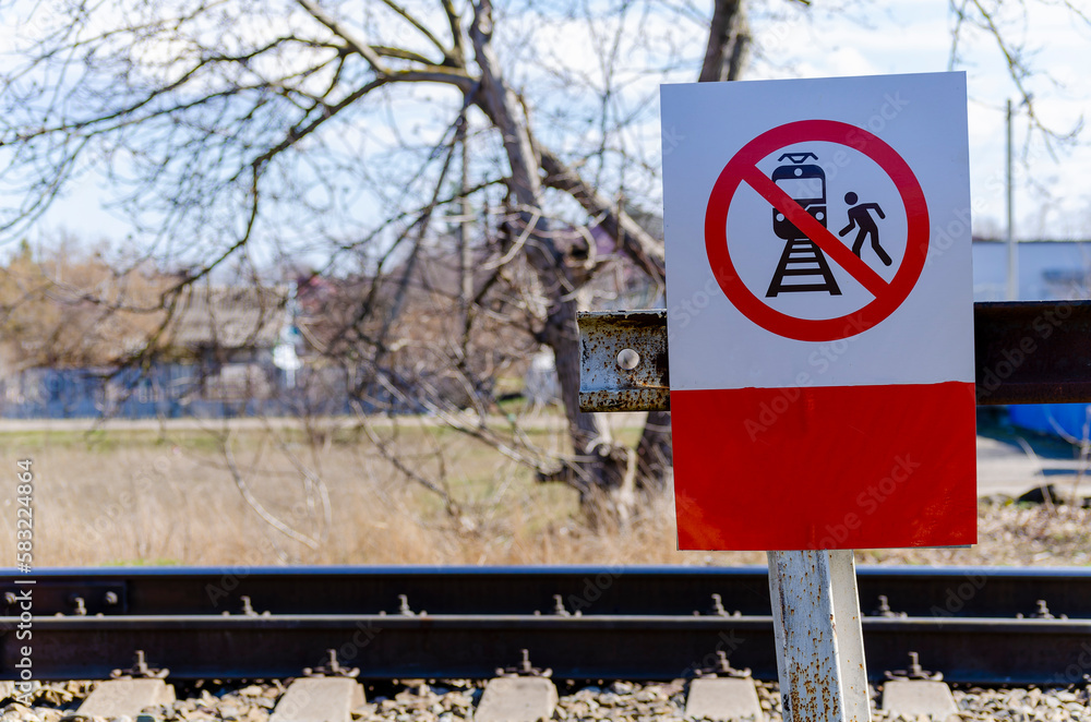 A red sign with a black silhouette of a person stepping on the railway ...