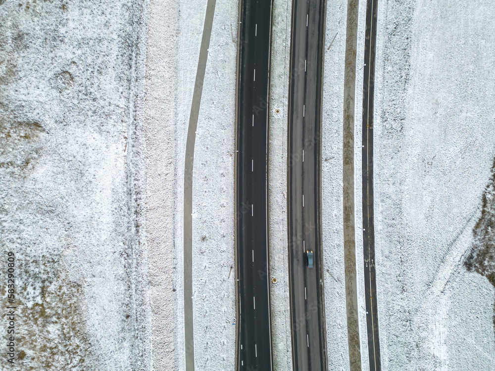Top view of the roadway in winter. Snow-covered road and roadside. The ...