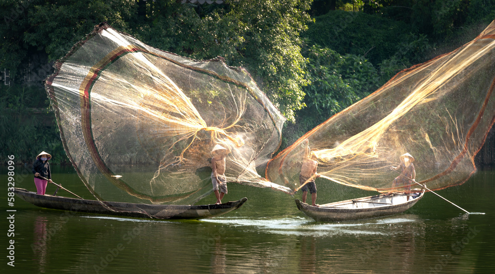 Foto de Vietnamese fishermen catching fish and throwing out two large ...