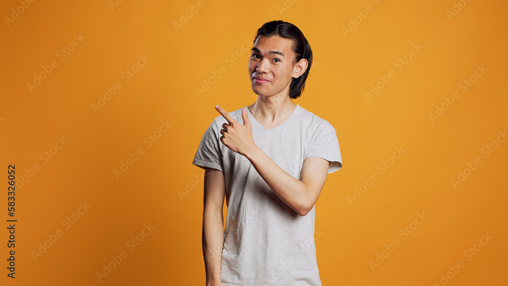 Asian person pointing sideways with index fingers, looking left or ...