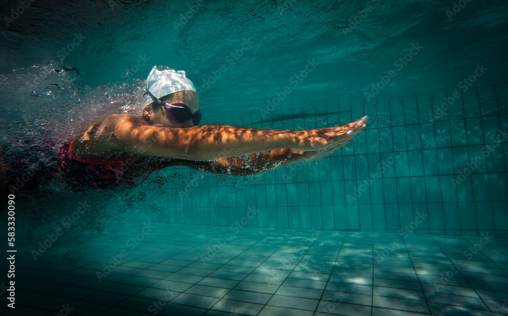 A talented female swimmer dives into a full-size tournament pool to ...