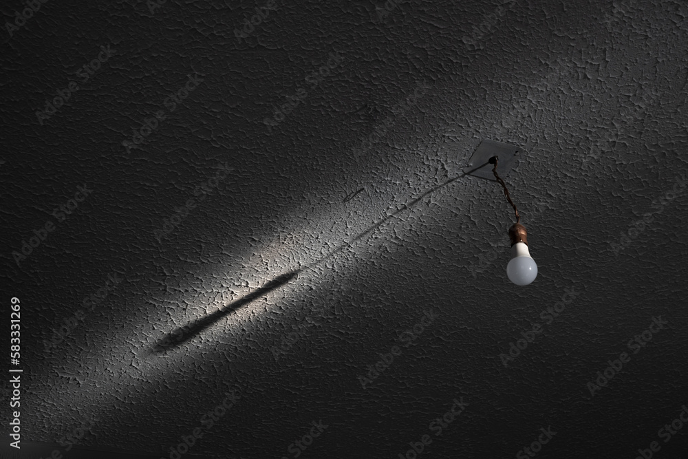 foco de techo colgando, apagado, con su propia sombra proyectada hacia ...