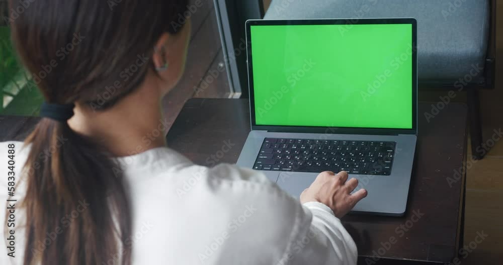 Freelancer female designer uses laptop with green screen mockup in cozy ...