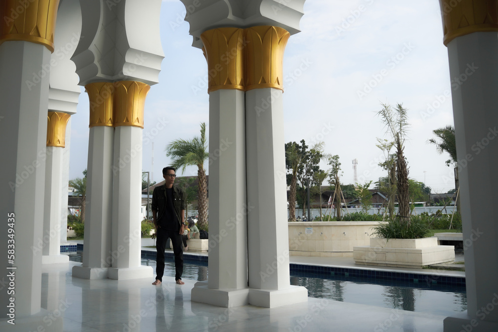 a man posing between the pillars of the beautiful mosque, at the Great ...