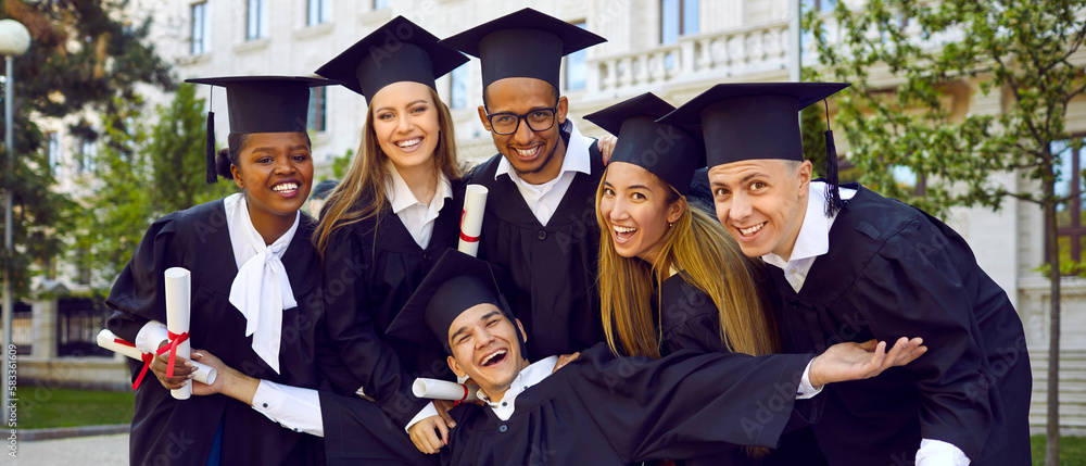 International smiling graduate people in gowns and caps with diplomas ...