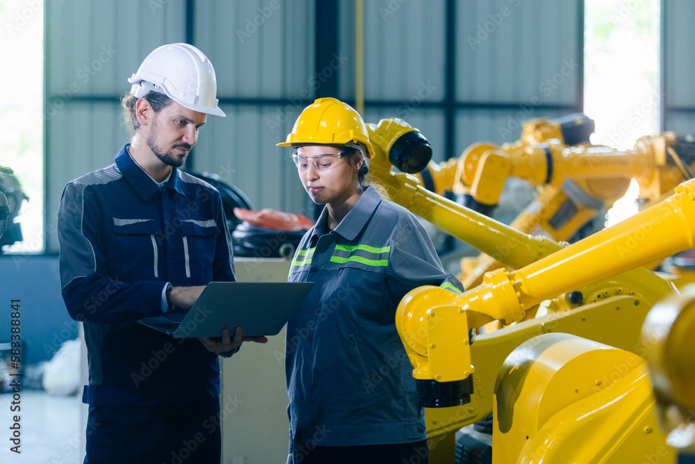 Engineers working robot assembly industry plant in factory using laptop examining condition ...