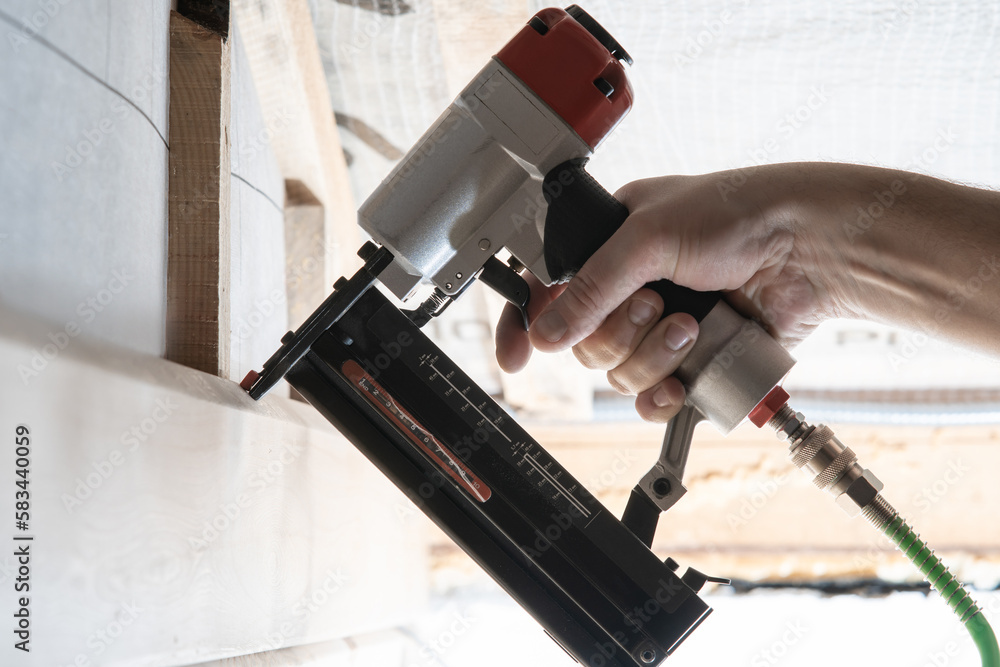 Cropped man hand hold pneumatic stapler nail gun for wooden timber ...