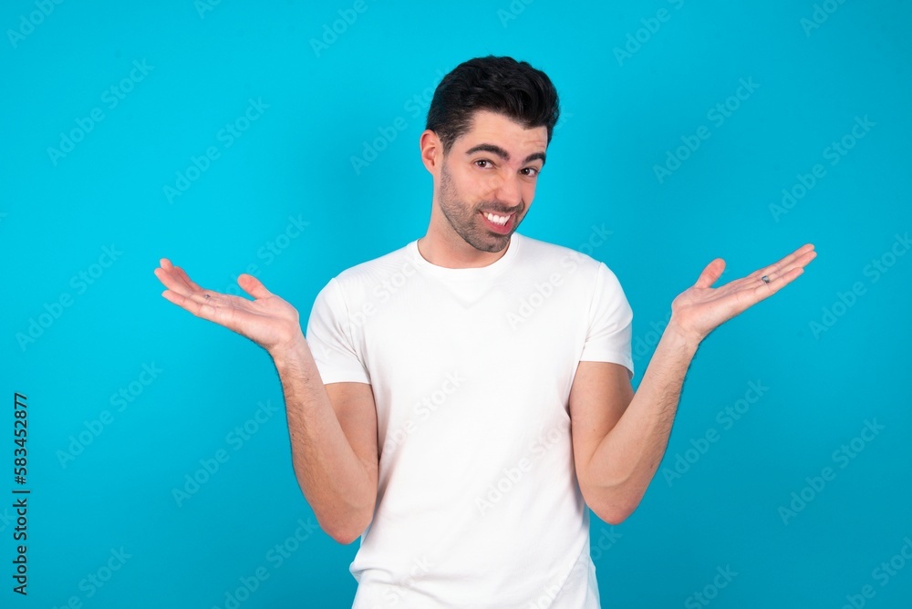Clueless Young man wearing white T-shirt over blue studio background ...