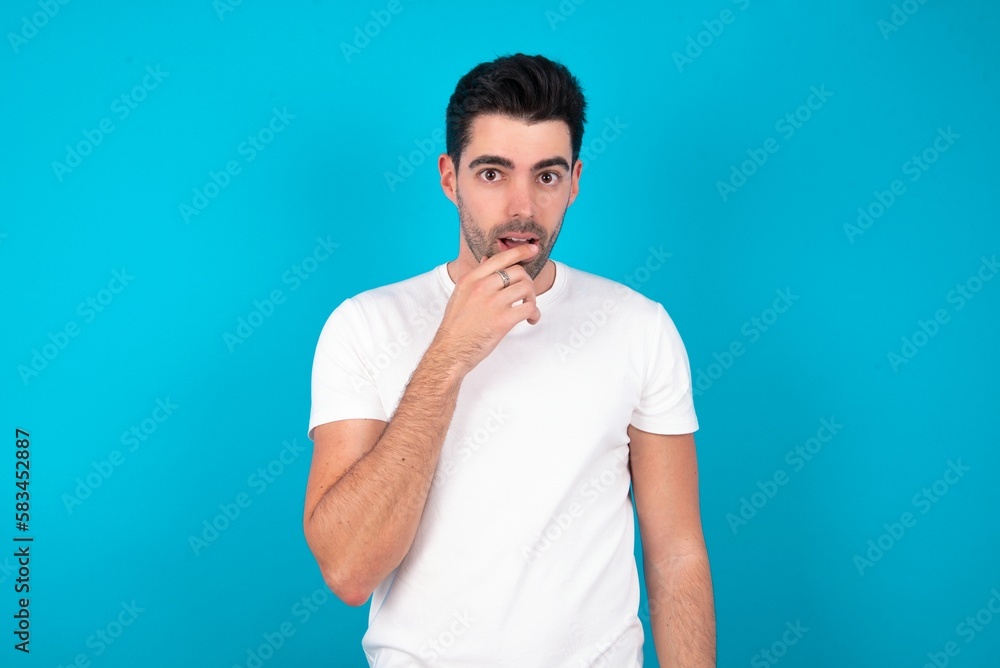 Nervous puzzled Young man wearing white T-shirt over blue studio ...