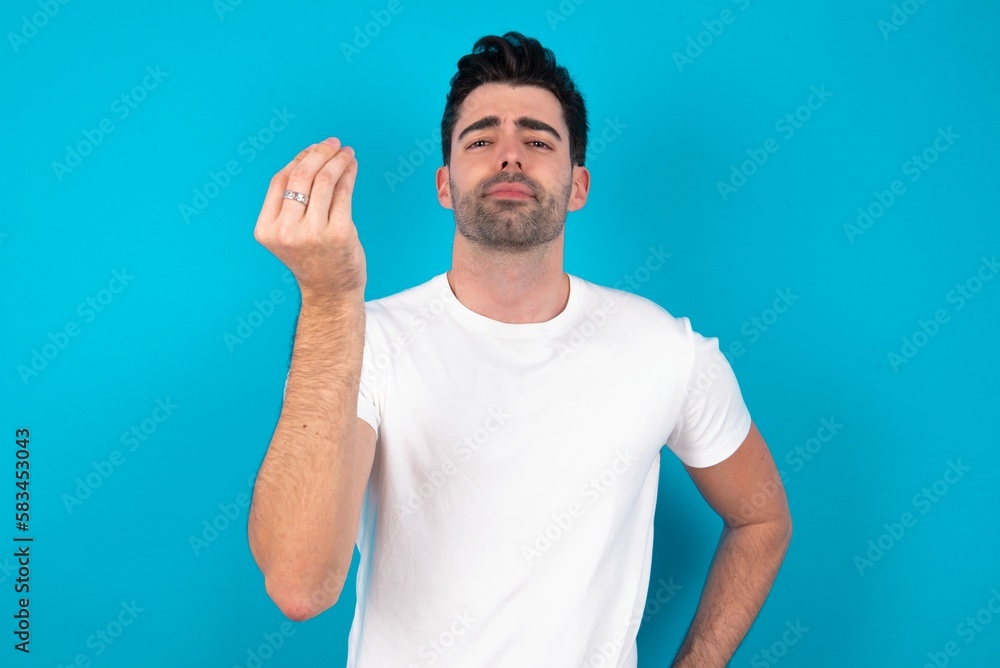 Young man wearing white T-shirt over blue studio background angry ...