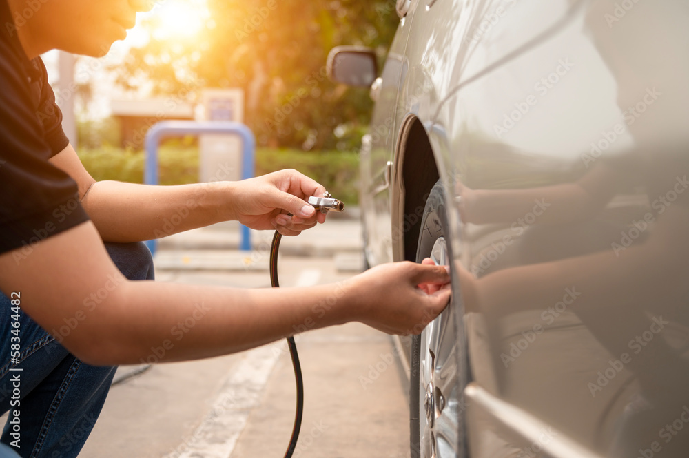 Asian man inflating tires at gas station And he's looking at the dial ...