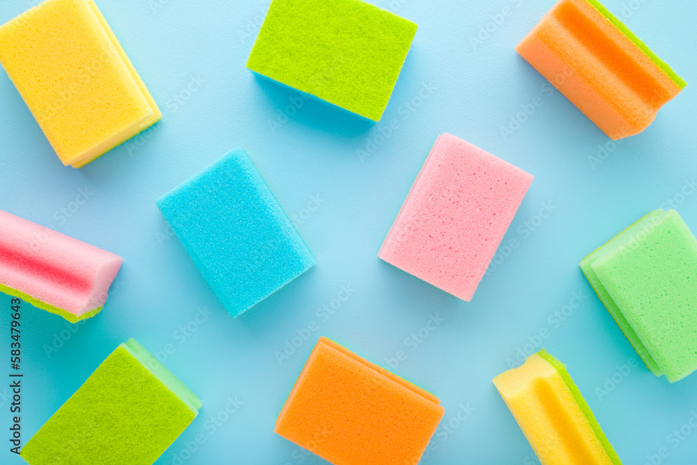 New colorful dry sponges on light blue table background. Pastel color ...