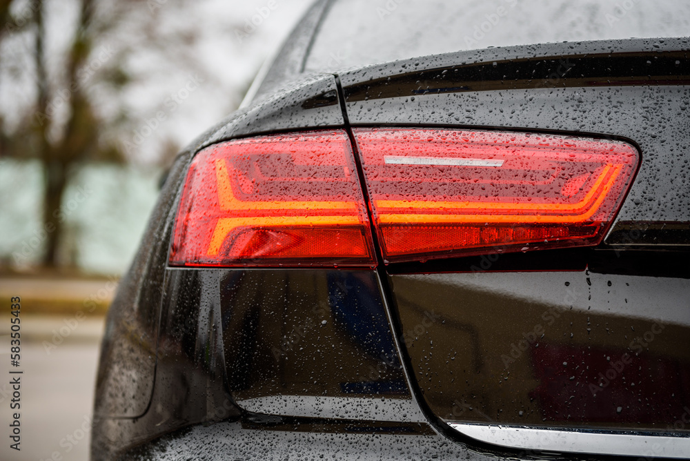 Car tail light. Detail black metallic car with rear light close up ...