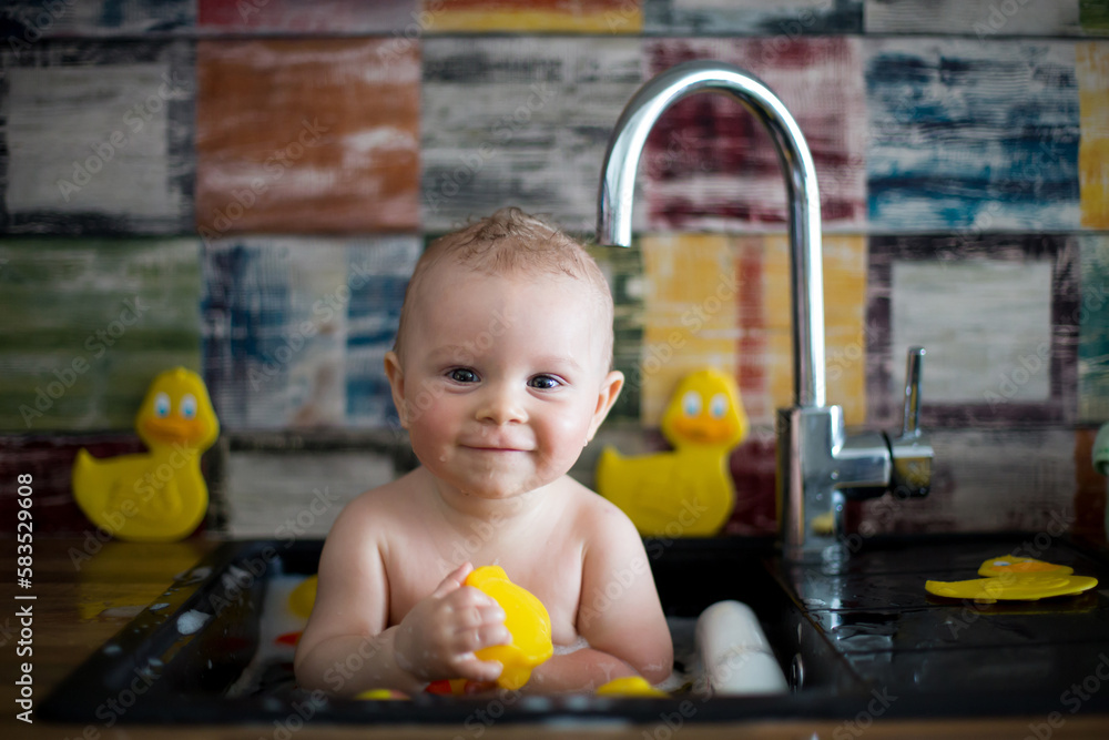 Cute snmiling baby taking bath in kitchen sink. Child playing with foam ...