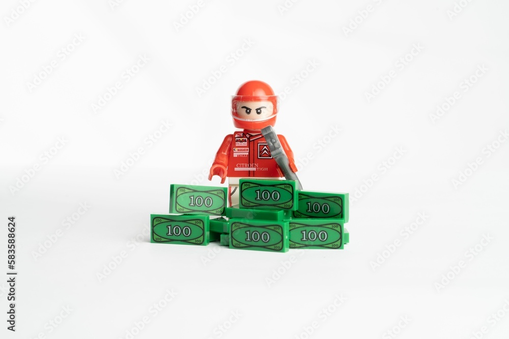 Figurine of a race car driver standing in front of lego 100 dollar ...