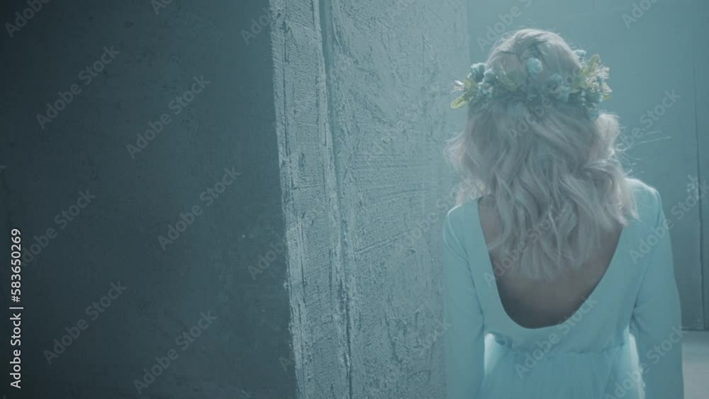 Rear back view of blonde woman walking inside dark maze with bridal ...