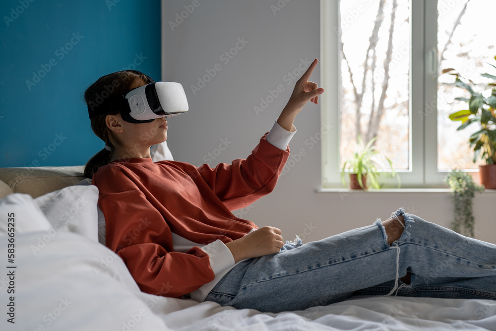 Teen girl wearing virtual reality headset interacting with digital ...